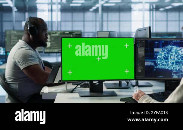IT support workers in AI data center coding on green screen computers ...