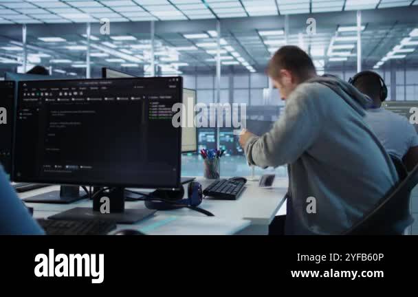 Technician arriving at work in high tech server room, analyzing data on ...