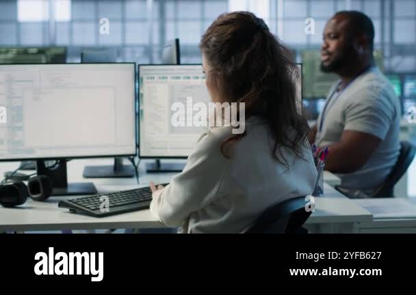 Employee sitting next to african american coworkers in data center doing checkup on electronics ...