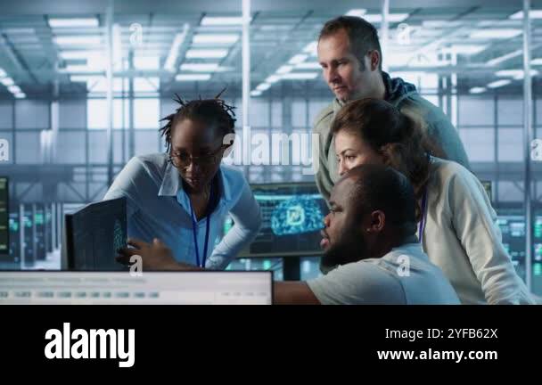 Multiethnic team of engineers working in server hub, using PCs to analyze data. Multiracial ...