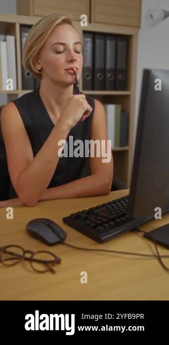 Young woman in an office room contemplating while holding a pen near ...