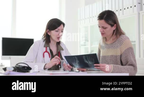 Woman doctor shows X-ray image of feet to female patient at desk. Medic ...