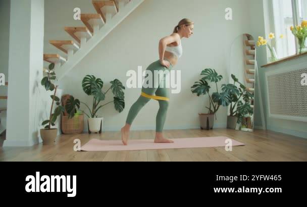 Profile view of a woman performing a leg lift with a resistance band ...