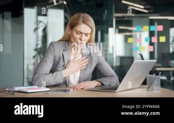 Sick businesswoman in a jacket suffering from chest tension, heart ...