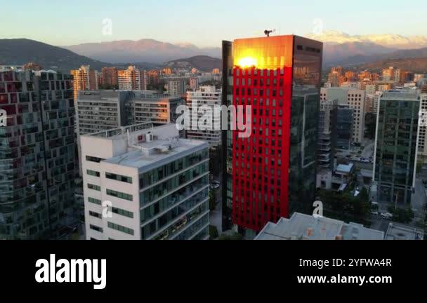 An aerial shot moving towards a distinctive red high-rise building in a ...