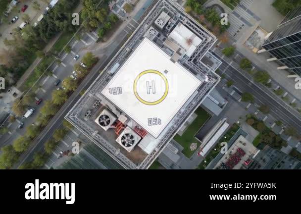 A descending aerial shot capturing a rooftop helipad on top of a high ...