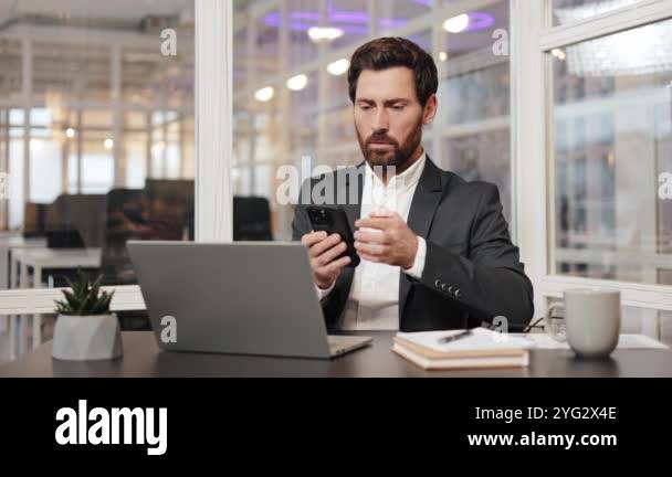 Male employee businessman sits at his desk in the office, looking ...