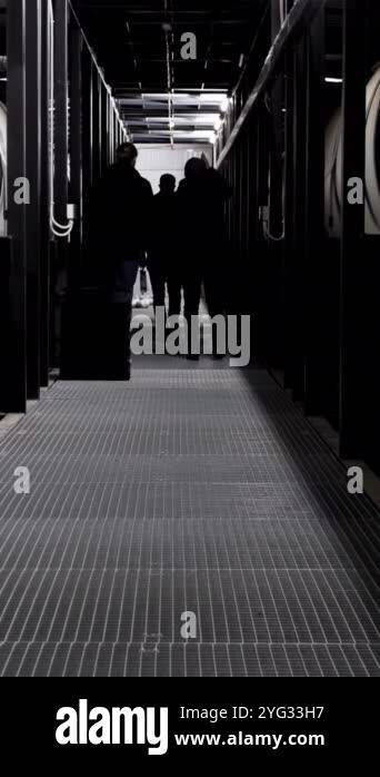 Rear view of three men walking along water treatment tanks at the power ...