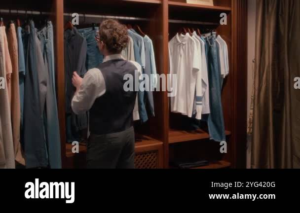 Caucasian salesman assisting African American male customer trying on ...