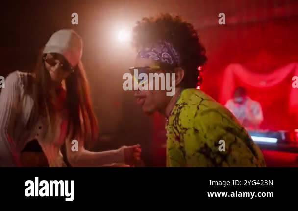 Positive young man with glasses clapping hands while dancing at club ...