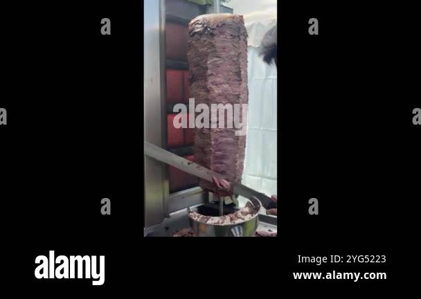 The chef cuts the traditional Turkish food Doner Kebab. A cook cuts ...