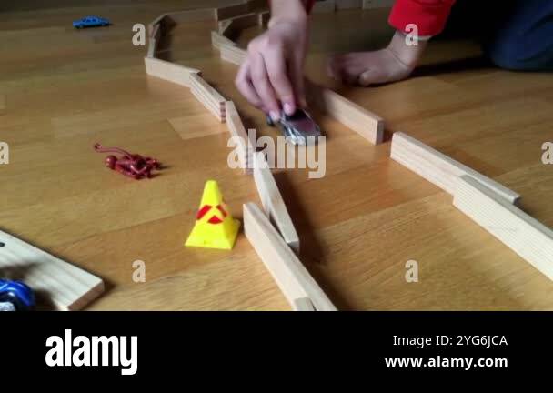 Hands pushing toy car along a wooden block pathway, creating a fun and ...