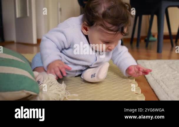 Baby sitting on mat, exploring surroundings with hands, engaging in ...