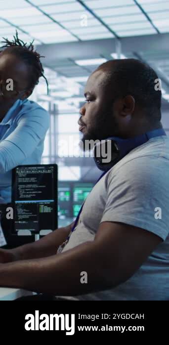 System administrator working with colleague in data center providing computing resources for ...