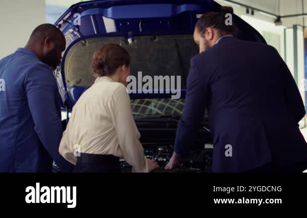 Salesman showing components under car hood for customers, hoping to ...