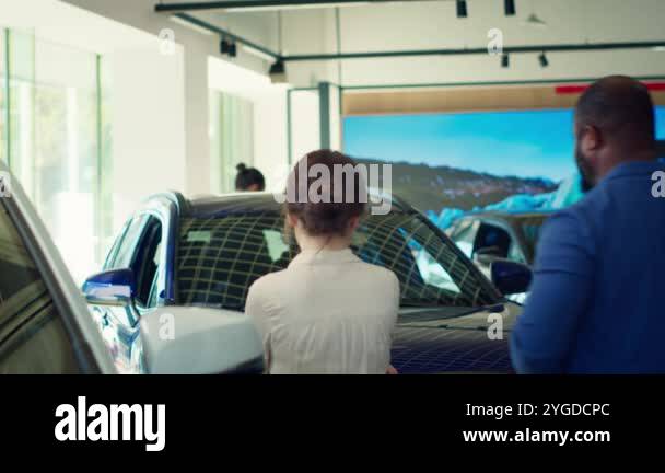 Customers walking in car dealership browsing through available models ...
