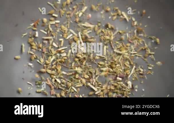 Dried yarrow (Achillea millefolium) falling into a gray bowl ...