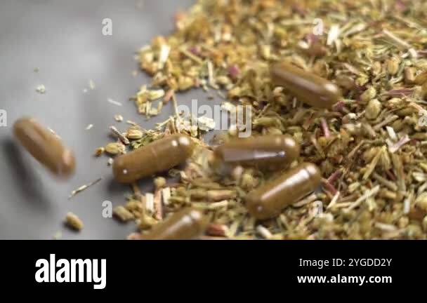 Herbal supplement capsules falling in slow motion on a pile of dried ...