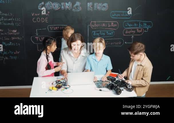 Diverse student writing engineering code while boy fixing mother board. Teacher giving advice ...