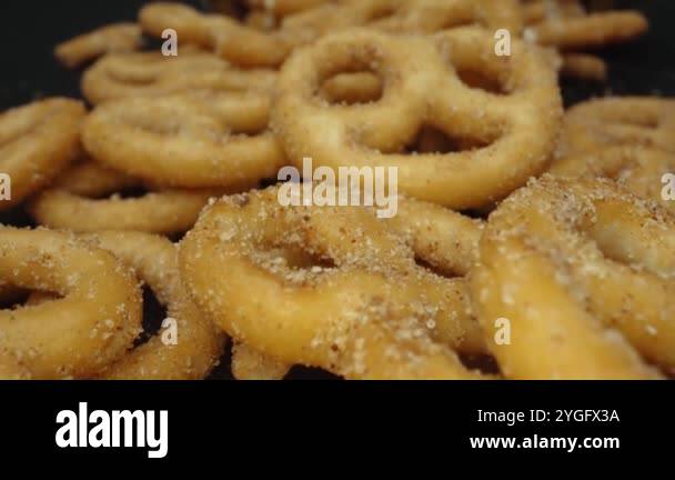 Close up of salted pretzel falling and scattering at black background ...