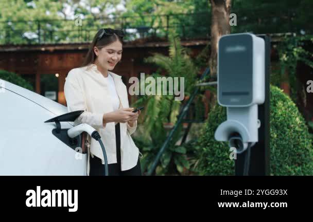 Sustainable urban commute with young woman pay electricity for EV ...