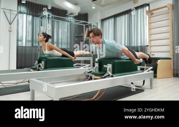 Man and woman practicing back extension exercises on pilates chair to ...