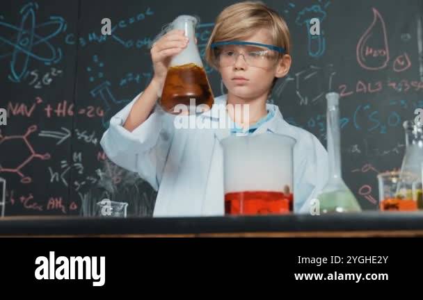 Smart boy inspect mixed chemical liquid in laboratory beakers while ...