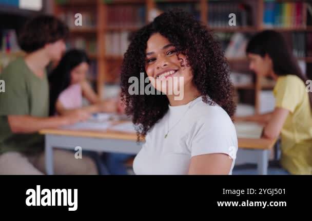 High school girl poses looking smiling at camera sitting in library ...