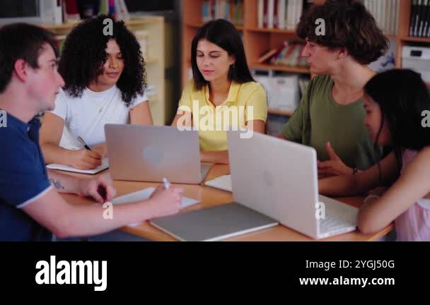 Young Caucasian man sits taking notes in notebooks in concentration as ...