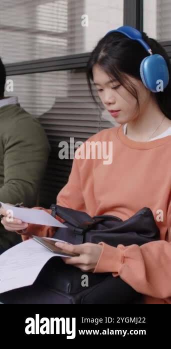 Vertical side shot of young Chinese girl in headset preparing for visa ...