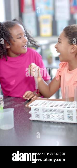 Vertical video: In school, two girls are enjoying chemistry experiment ...