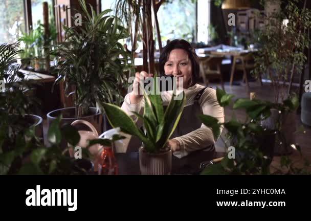 Flower designer streaming live video. Plant shop owner holding ...