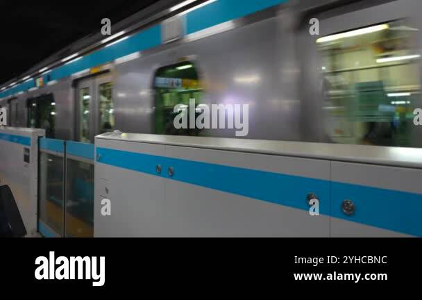 An electric train approaches a modern subway platform in Tokyo, Japan ...