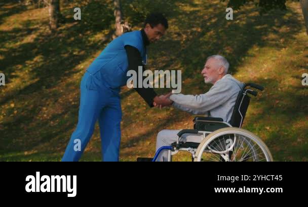Hispanic doctor taking care of old disabled friend in wheelchair. Latin ...
