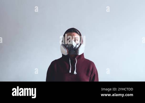 A young attractive girl puts a gas mask on her head and shows how to ...