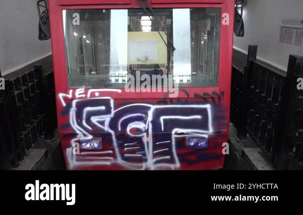A red train marked with graffiti is stationed within an underground ...