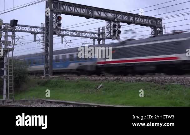 A high-speed train races through a railway intersection under cloudy ...