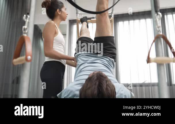 Pilates instructor guiding a client through an inverted leg raise ...