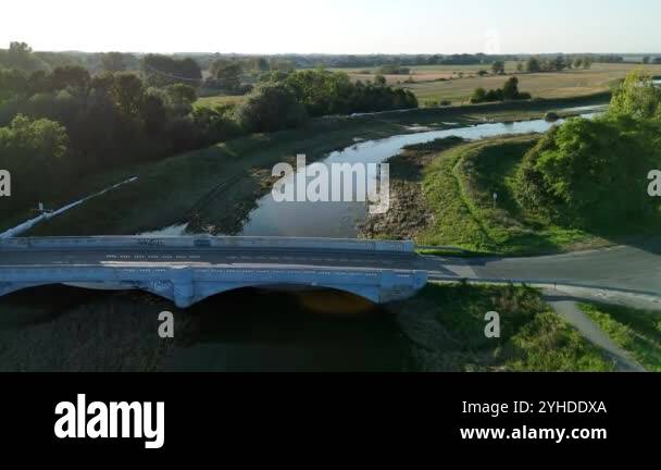 An aerial view captures a small bridge crossing a peacefully curving ...
