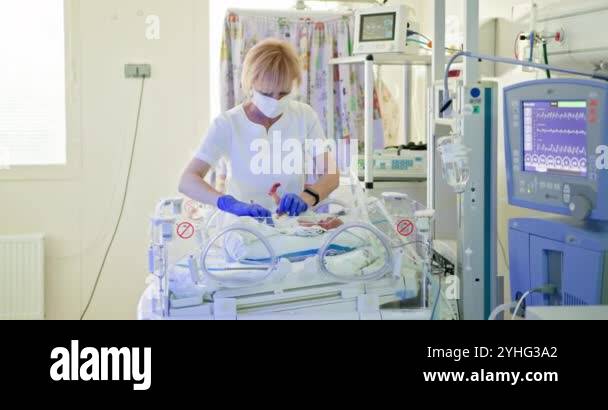 Nurse providing critical care to newborn in hospital intensive care ...