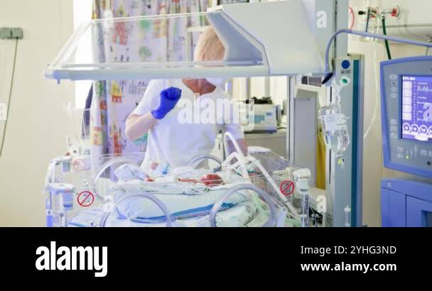 Nurse providing care to newborn in neonatal intensive care unit ...