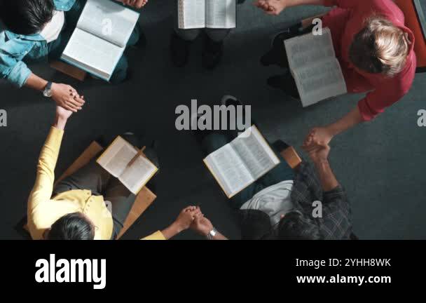 Top down view of diverse people holding hand and sitting in circle with ...