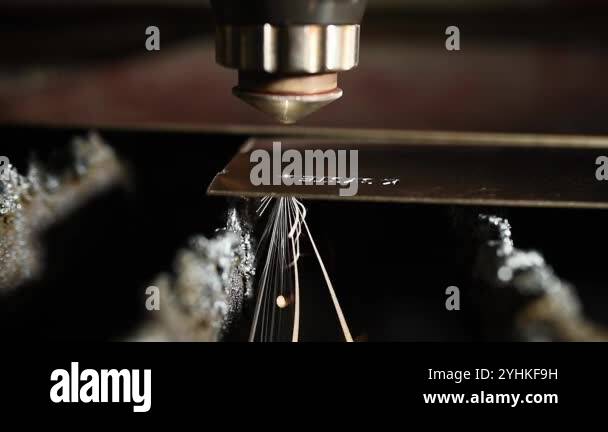 A CNC laser cutting machine precisely cuts through a metal sheet, producing bright sparks. This ...