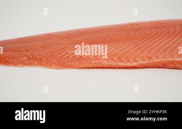 A piece of red fish fillet is shown on a white background. The concept ...