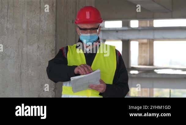 Work superintendent in medical protective face mask, goggles and red ...