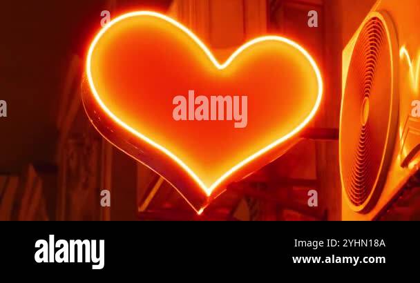 Red heart on the night street. There is an air conditioner and bright ...