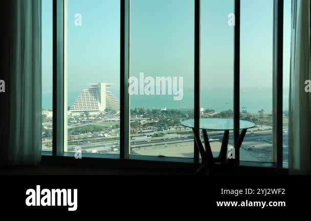 Shore of Persian Gulf in Doha city. View from big window in hotel room ...