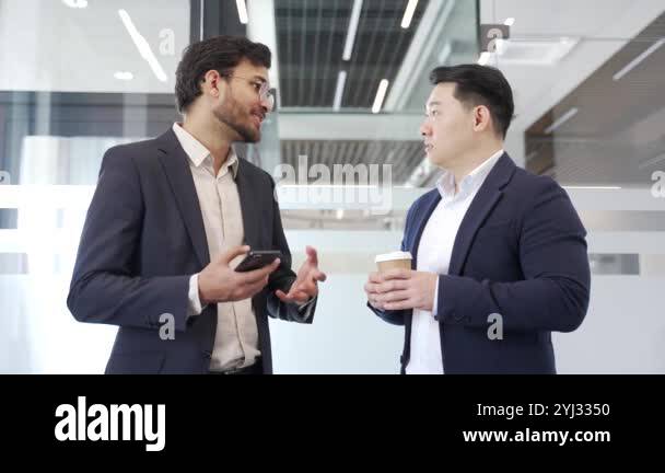 Two professional businessmen in suits engaging in casual discussion ...