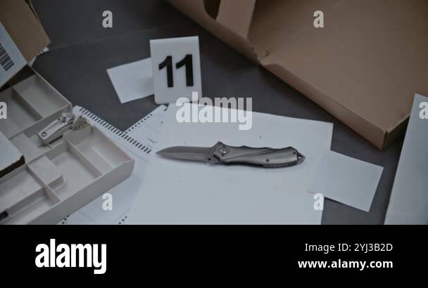 Close up of knife lying next to numbered marker. Papers, evidence and ...