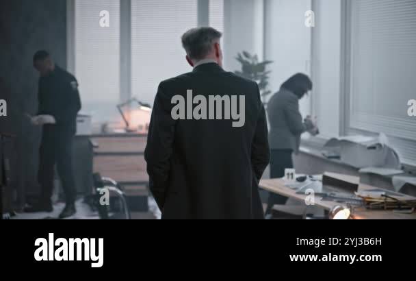 Office robbery case: Back view of male detective in suit examining ...